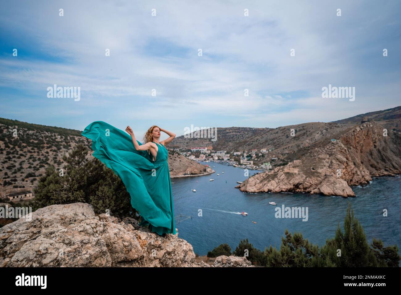 A woman in an emerald dress, a fashion model with long silk wings in a ...
