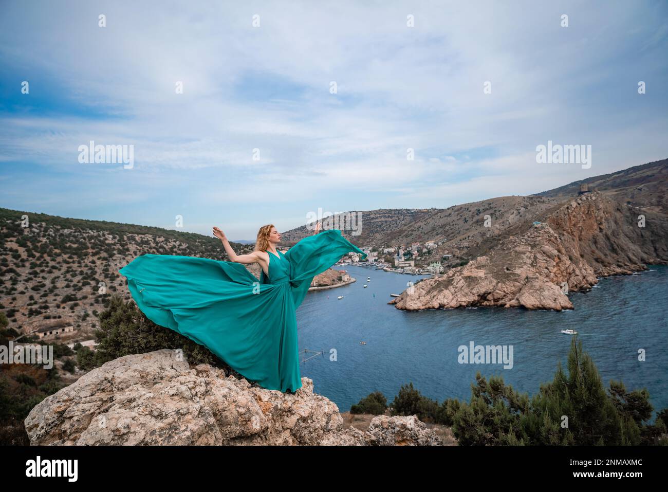 A woman in an emerald dress, a fashion model with long silk wings in a ...