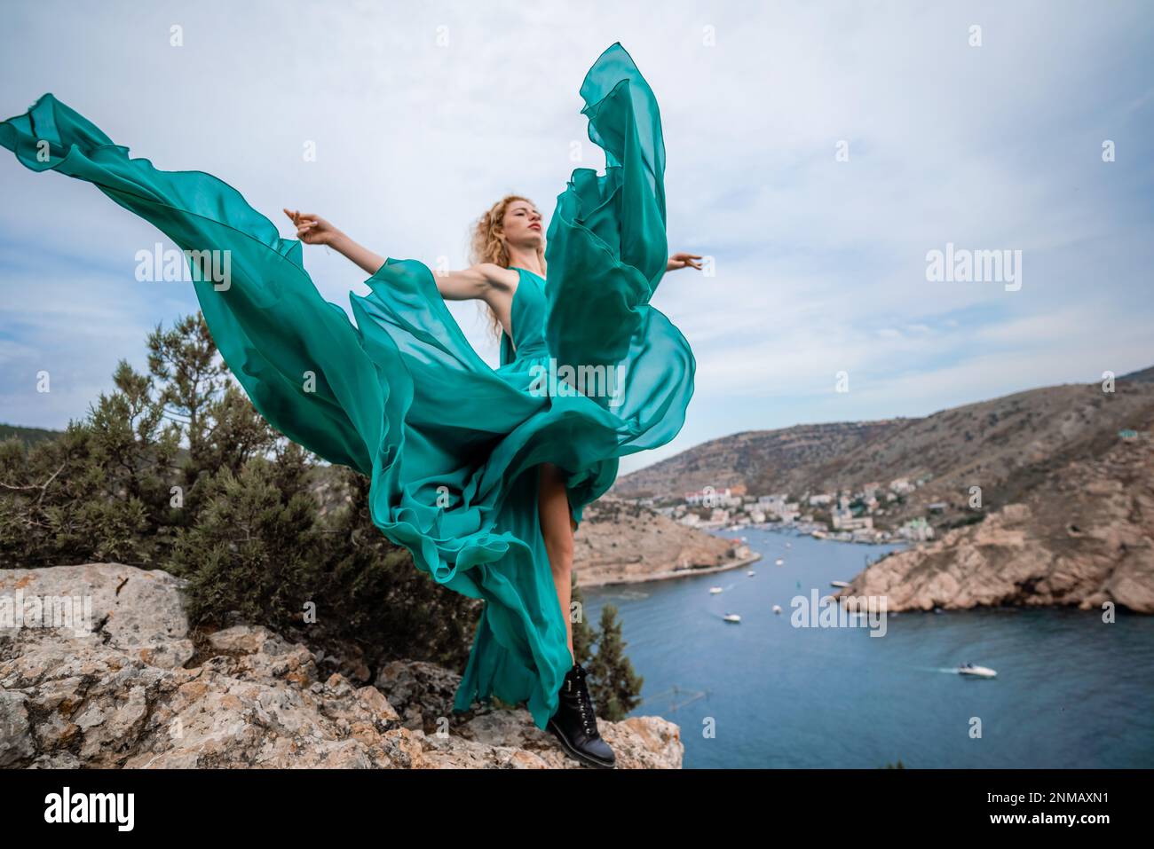 A woman in an emerald dress, a fashion model with long silk wings in a ...
