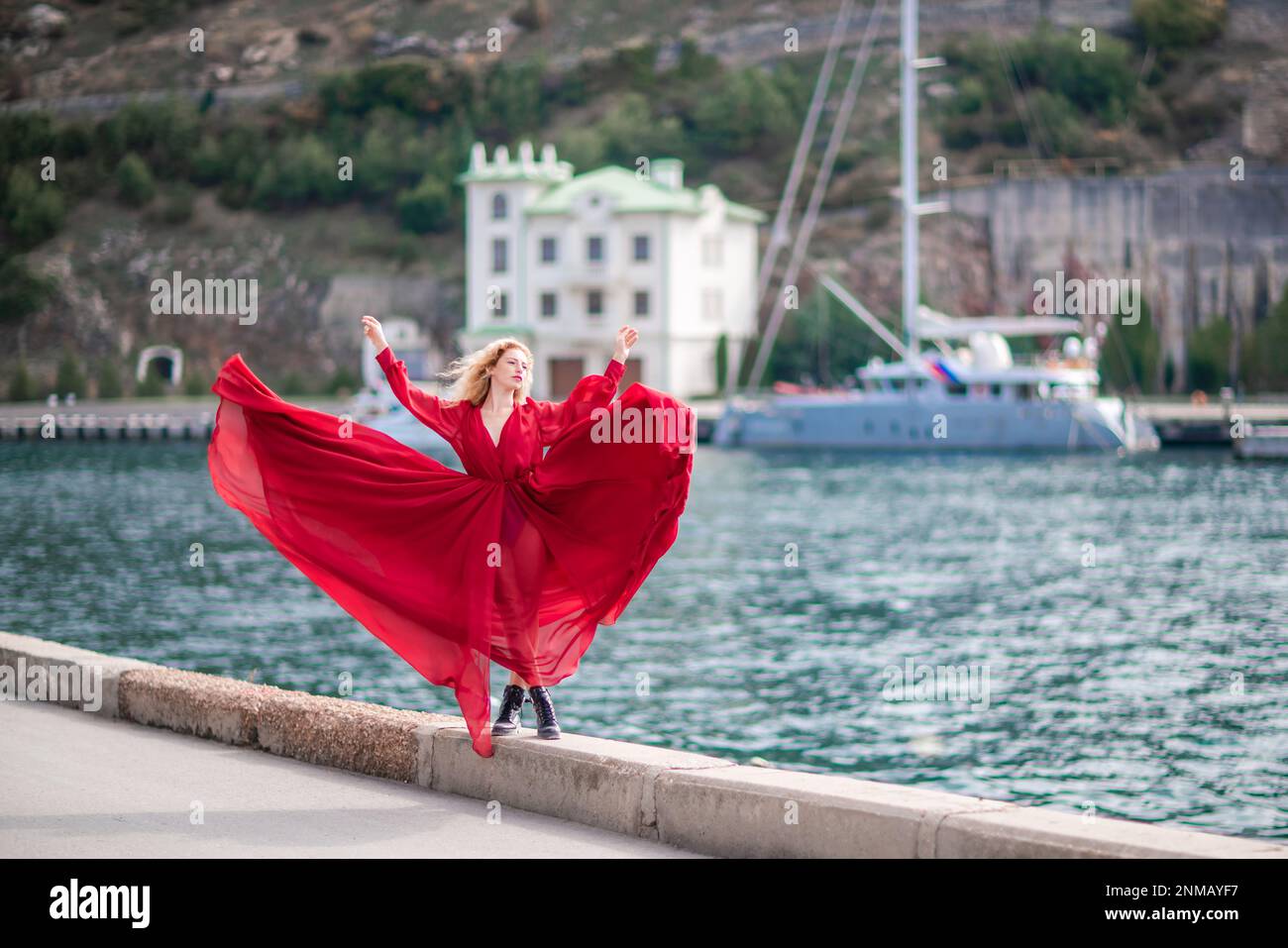 A woman in a red dress, a fashion model with long silk wings in a ...
