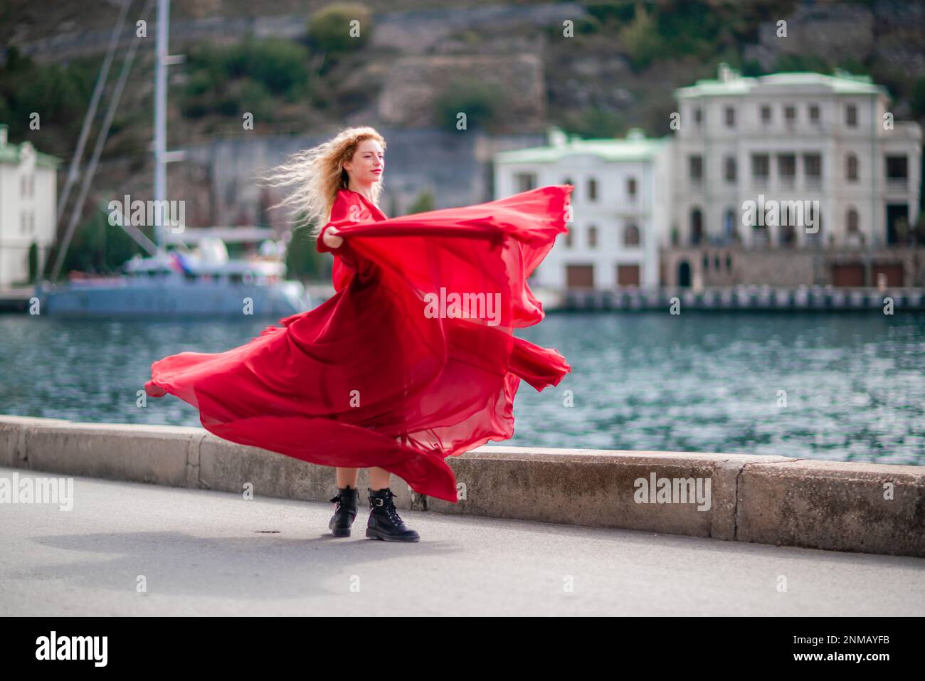 A woman in a red dress, a fashion model with long silk wings in a ...