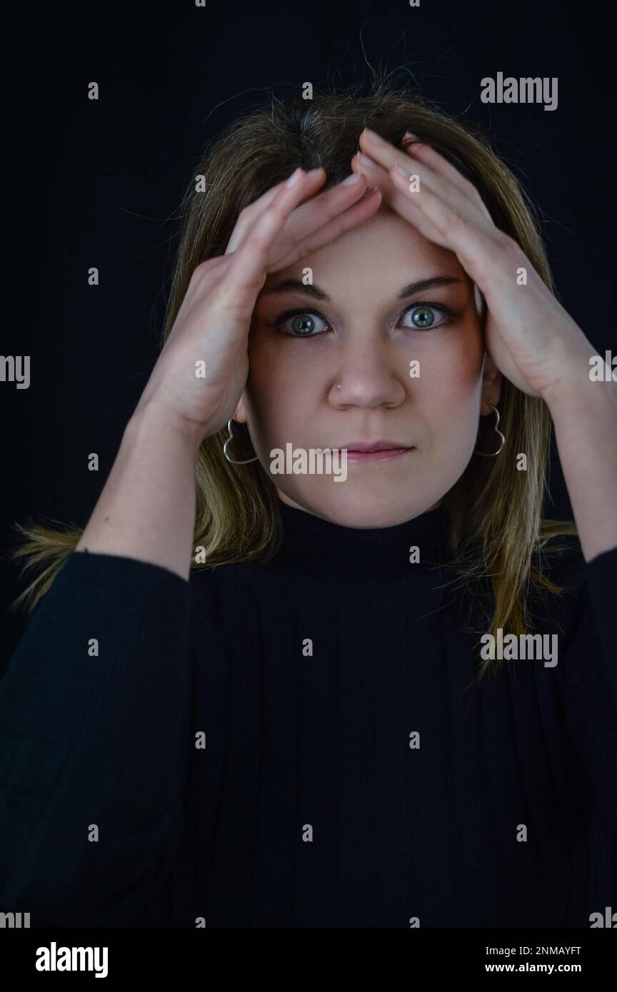 portrait of a beautiful blonde woman with her hands on her forehead ...
