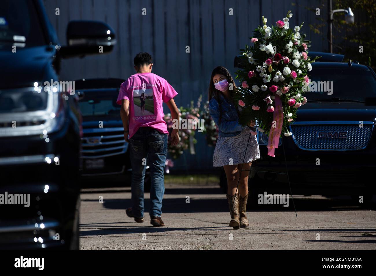 A person carries a flower arrangement from the funeral of Brianna ...