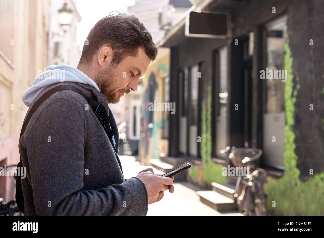 Man standing on street and using his phone, typing text, online ...