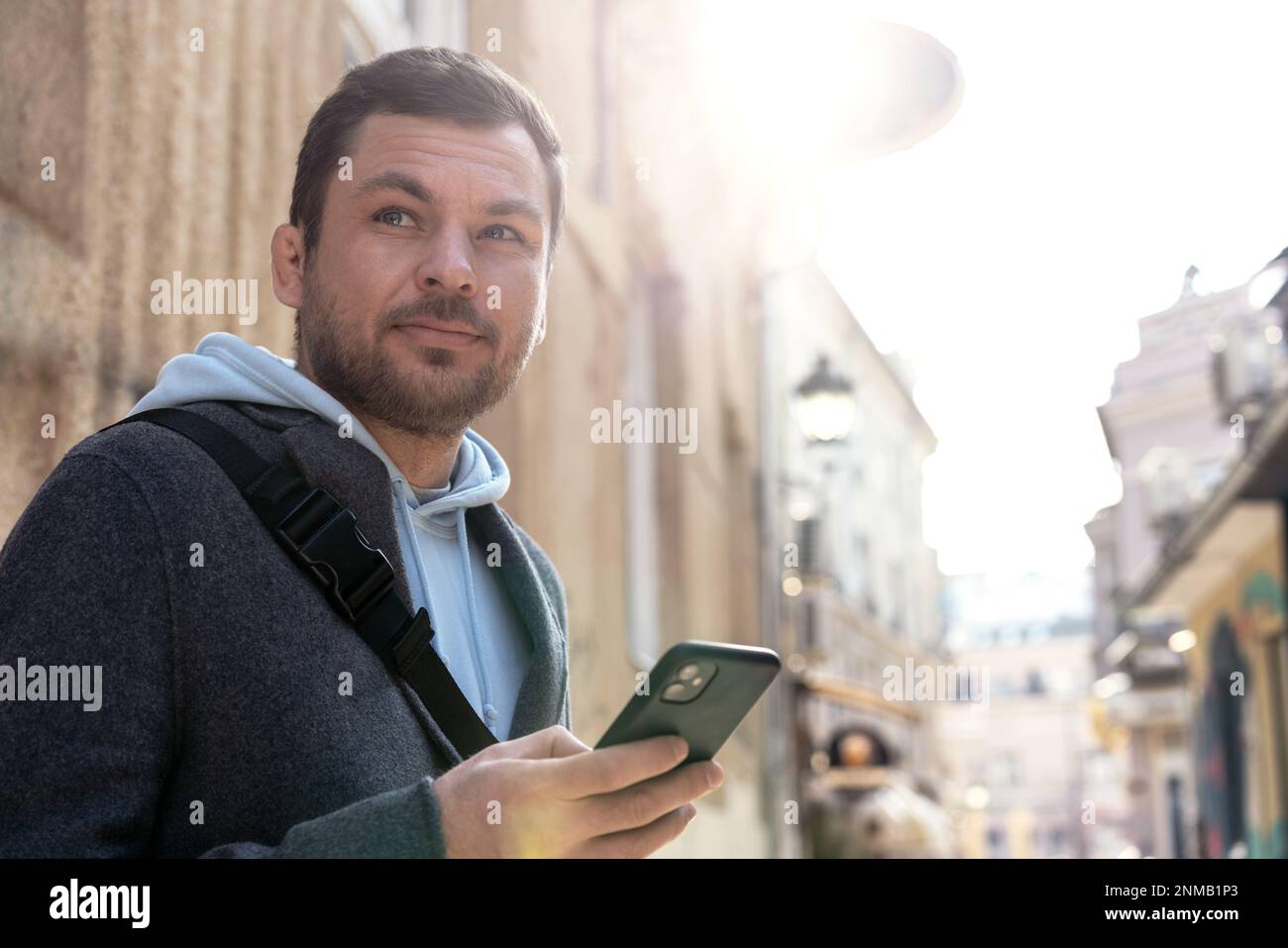 Portrait young adult man with mobile phone standing on street in ...