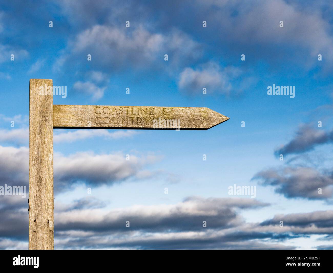 Coastline and countryside sign against a blue sky with cloud background ...