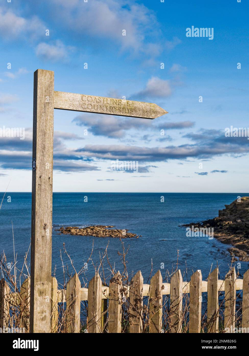 Coastline and countryside sign against a blue sky with cloud background ...