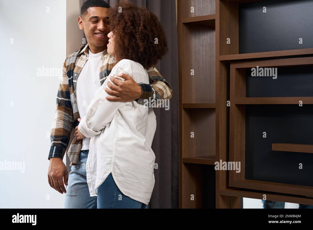 Multiracial couple stands embracing at the window in hotel room Stock ...