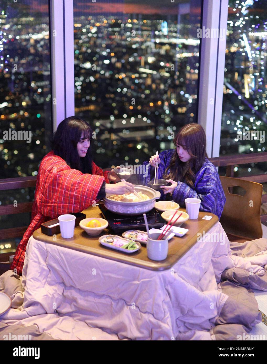 Female customers enjoy eating oden, Japanese fishcake stew on a kotatsu ...