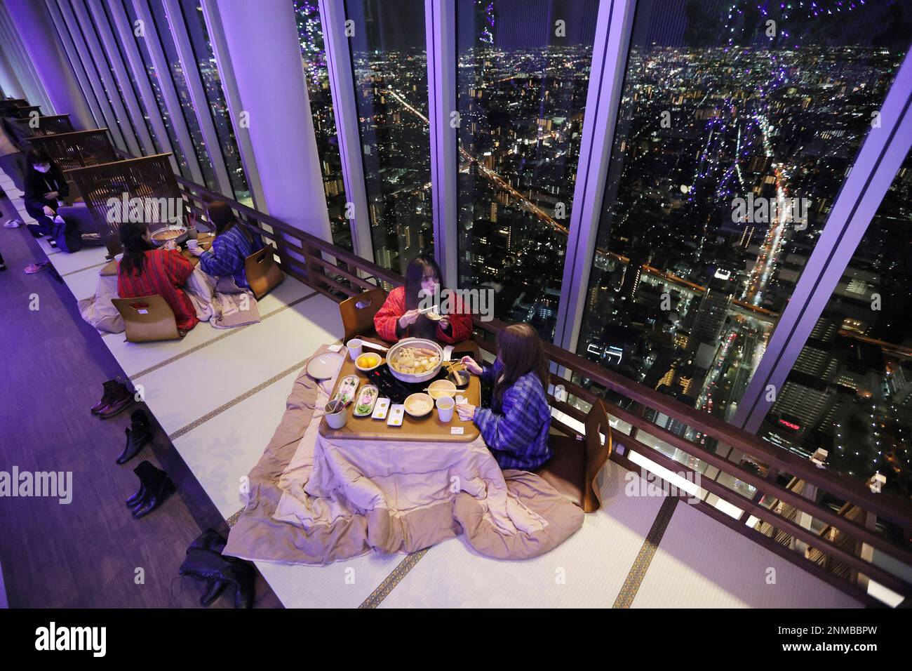 Female customers enjoy eating oden, Japanese fishcake stew on a kotatsu ...