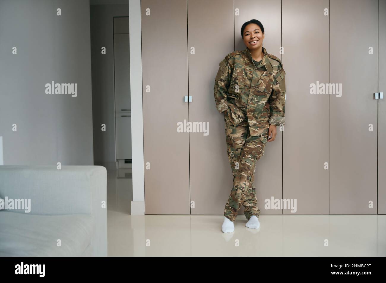 Happy military woman stands in a cozy living room Stock Photo - Alamy