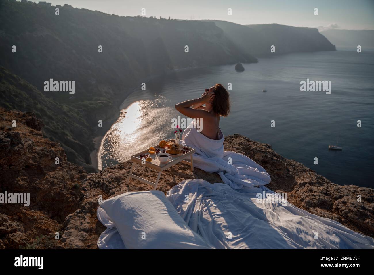 Woman wake up in bed wuth duvet and pillow over nature sea background ...
