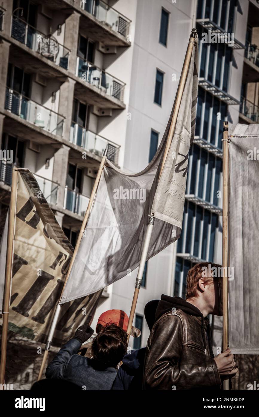 People with jackets and huge protest signs in urban area with high rise ...