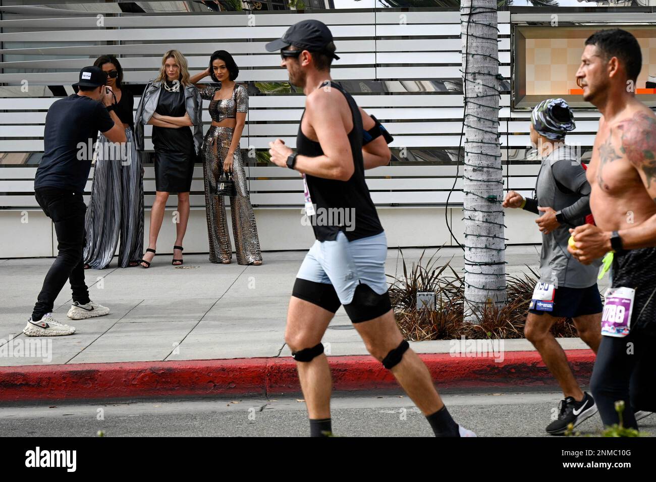 Runners head by a fashion shoot in progress along Rodeo Drive in ...