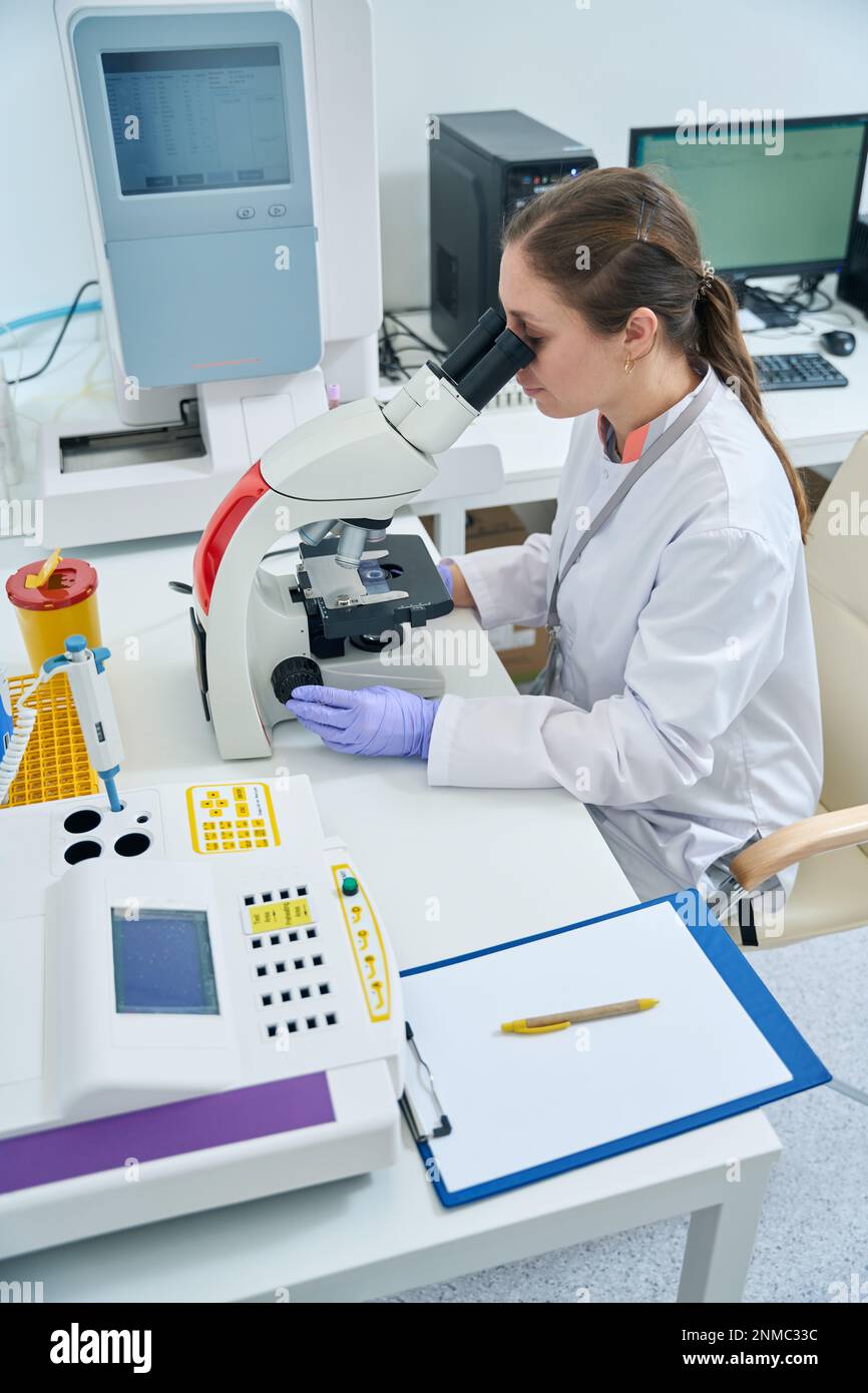 Hematologist examines a biomaterial sample through a microscope Stock ...