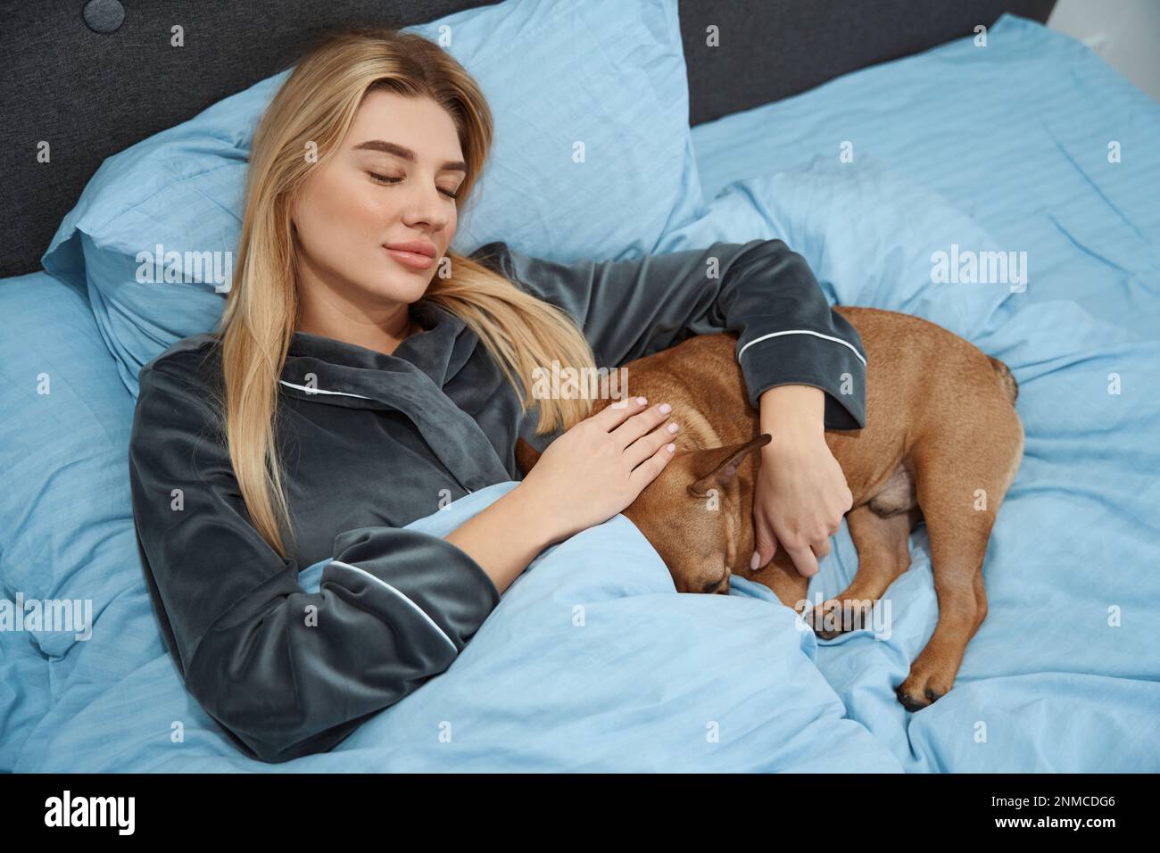 Serene woman dozing off with her dog in bedroom Stock Photo - Alamy