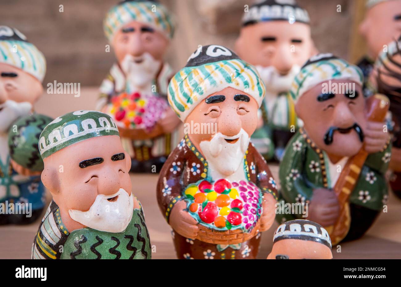 The clay figurines of happy old men in traditional Uzbek costumes are ...
