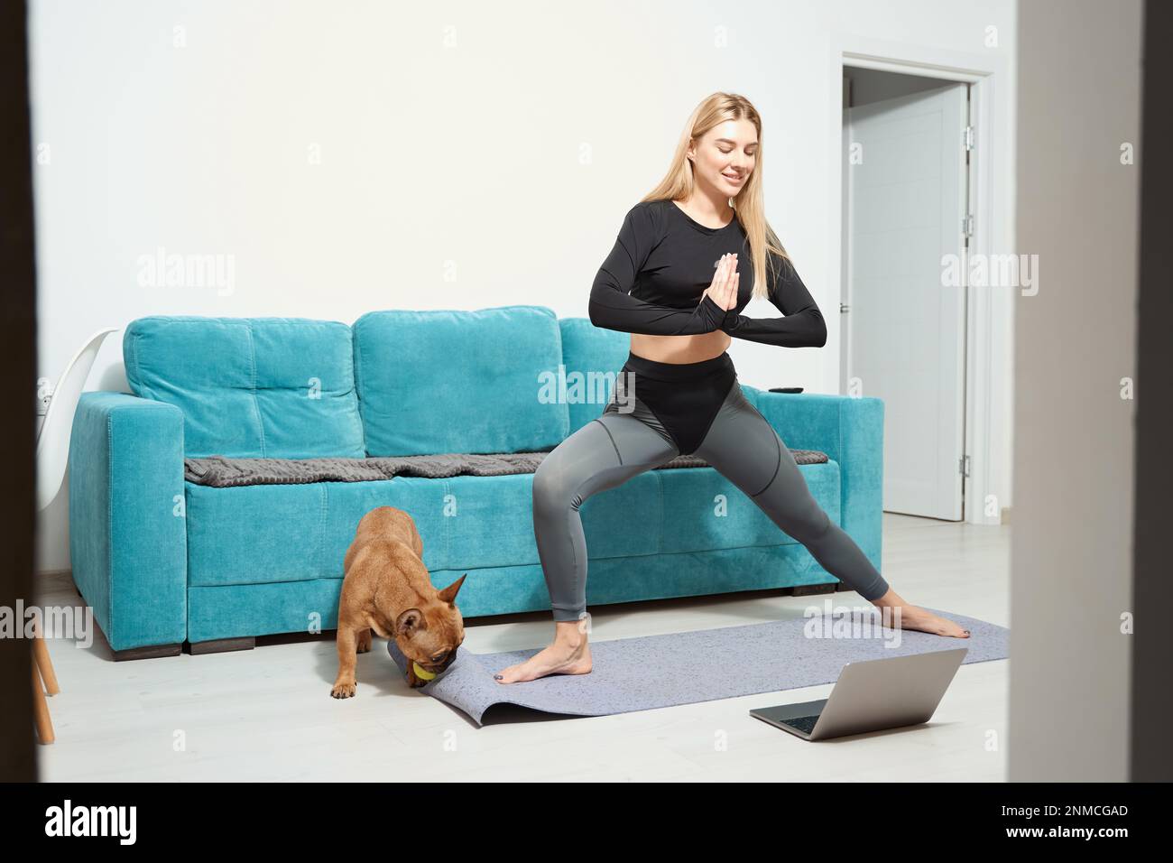 Joyous female doing lower-body exercise on yoga mat before laptop Stock ...