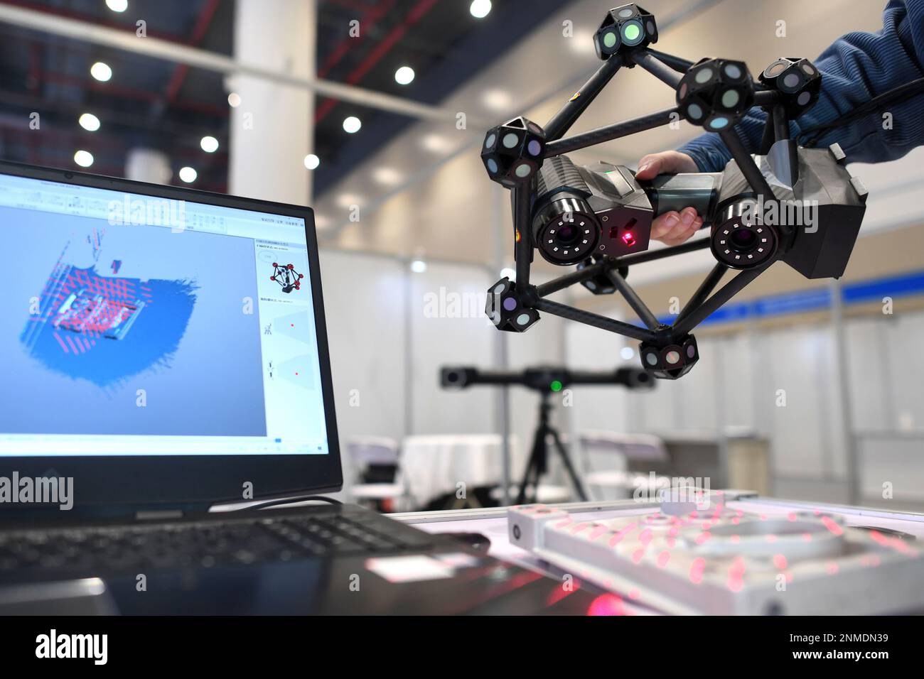 An exhibitor demonstrates a handheld 3D scanner that generates three ...