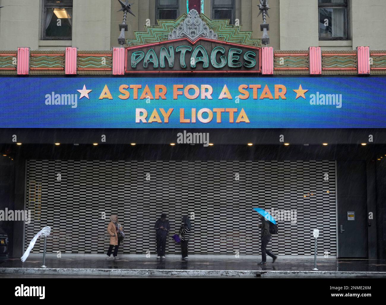 Pedestrians shield themselves from rain under a Pantages Theatre ...