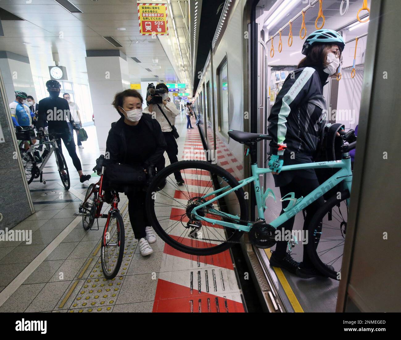 Tourists carrying their bicycles get on a train of Nishitetsu Tenjin ...