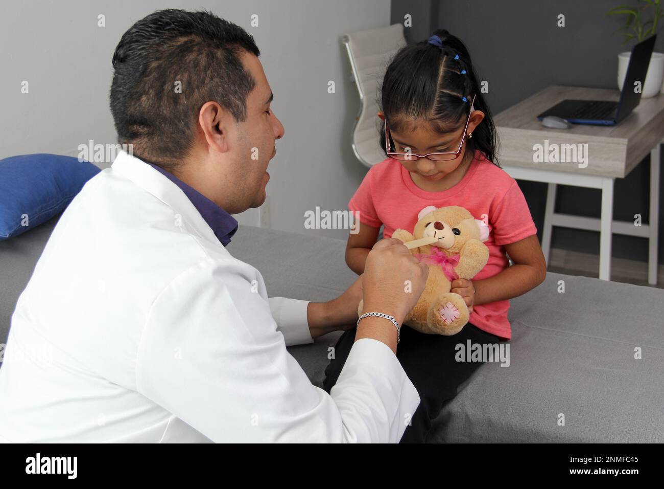 Latino pediatrician doctor checks his girl patient with autism spectrum ...