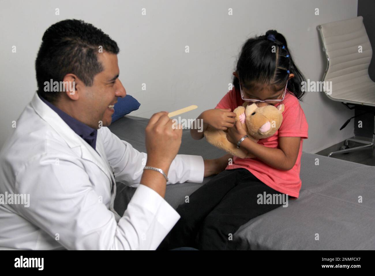 Latino pediatrician doctor checks his girl patient with autism spectrum ...