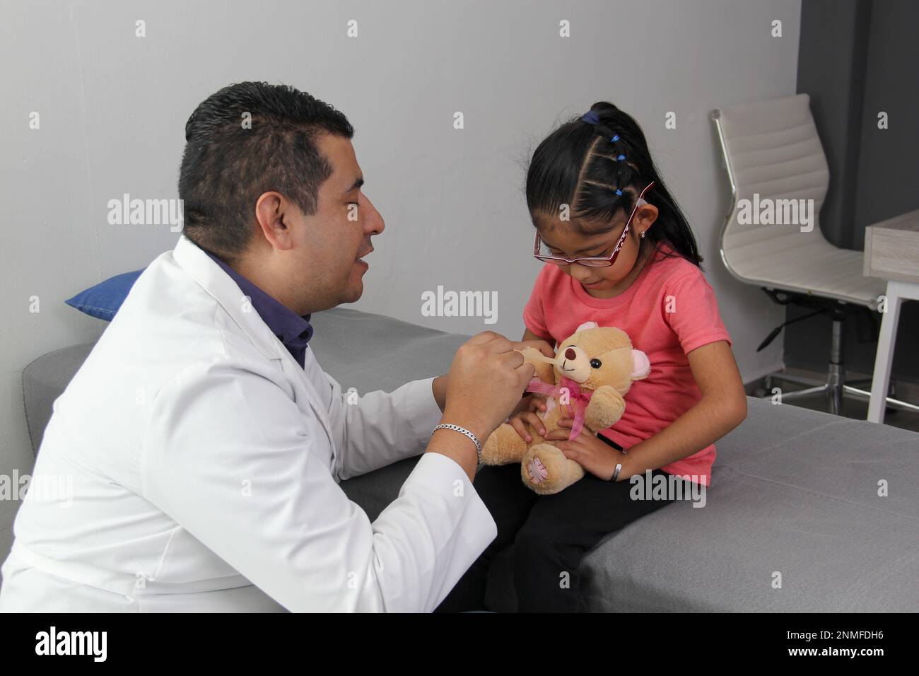 Latino pediatrician doctor checks his girl patient with autism spectrum ...