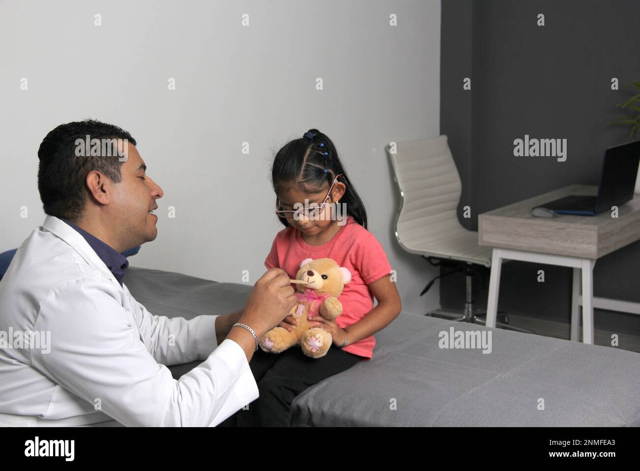 Latino pediatrician doctor checks his girl patient with autism spectrum ...