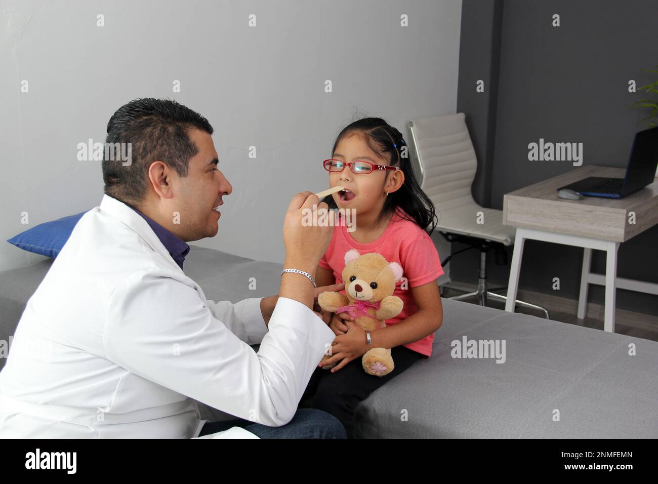 Latino pediatrician doctor checks his girl patient with autism spectrum ...