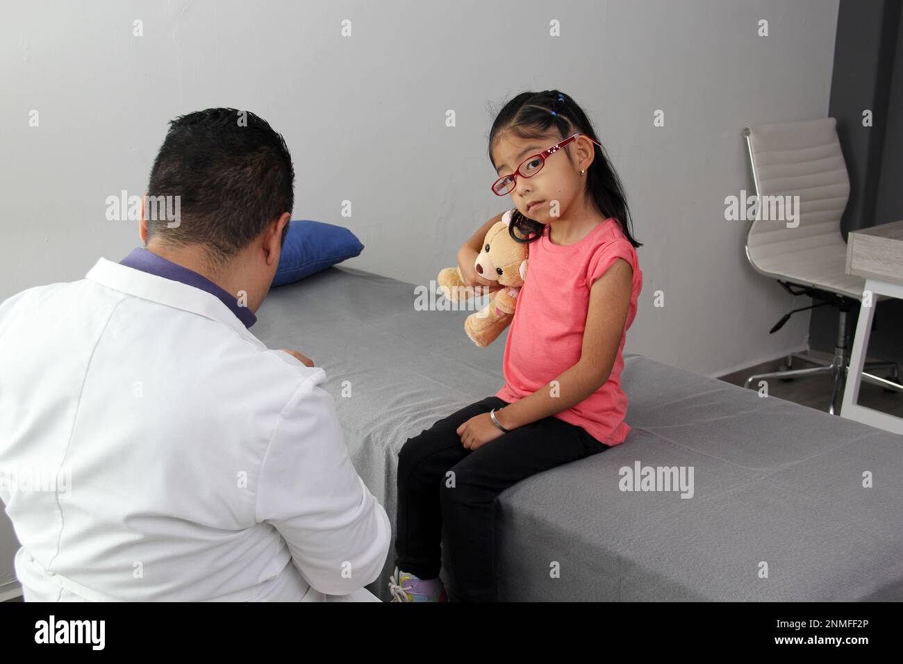 Latino pediatrician doctor checks his girl patient with autism spectrum ...