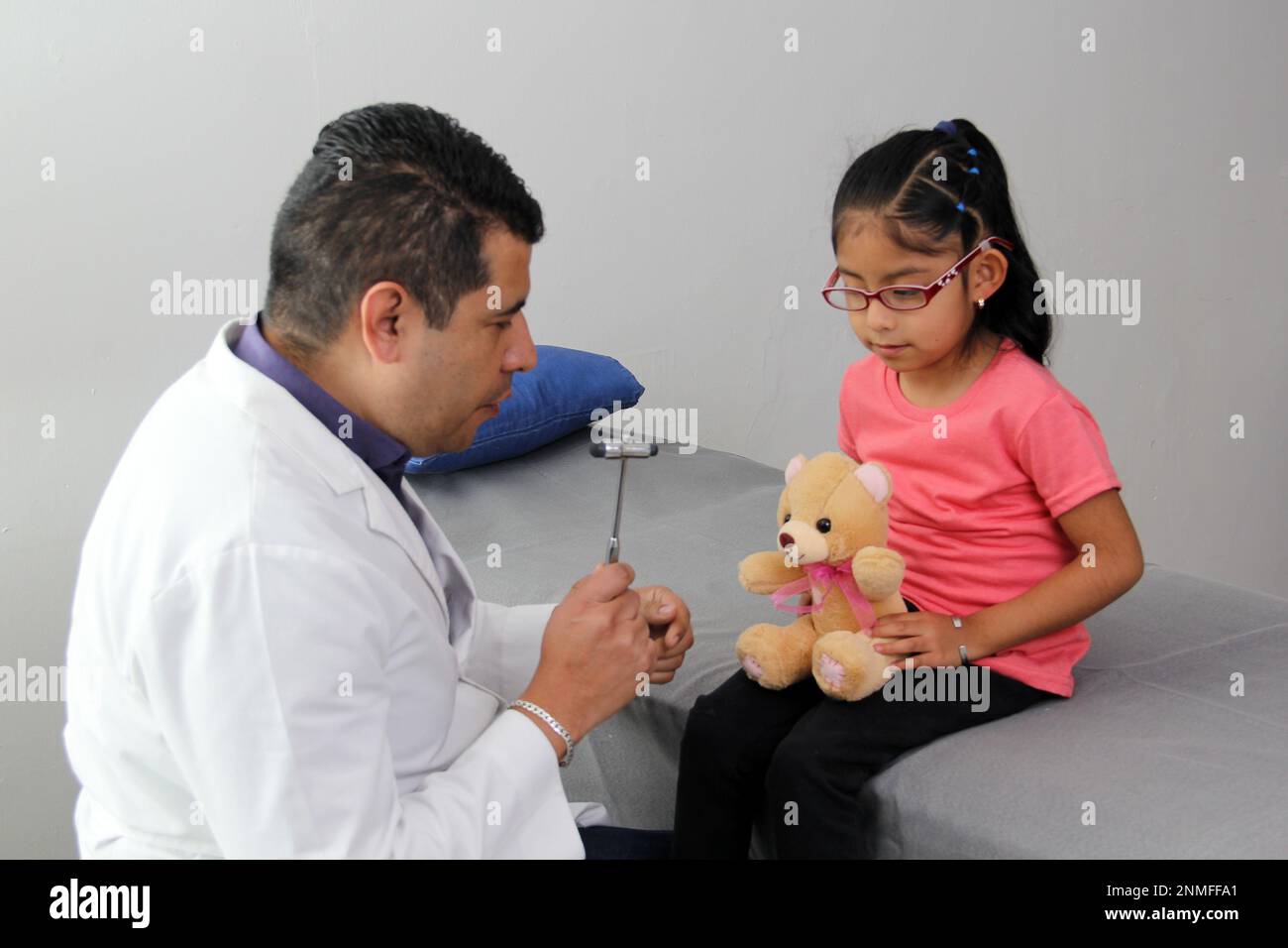 Latino pediatrician doctor checks his girl patient with autism spectrum ...