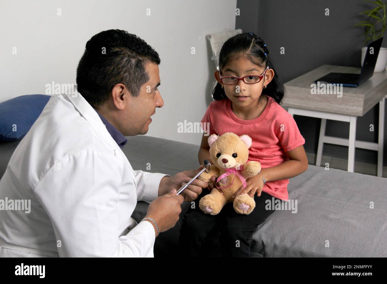 Latino pediatrician doctor checks his girl patient with autism spectrum ...