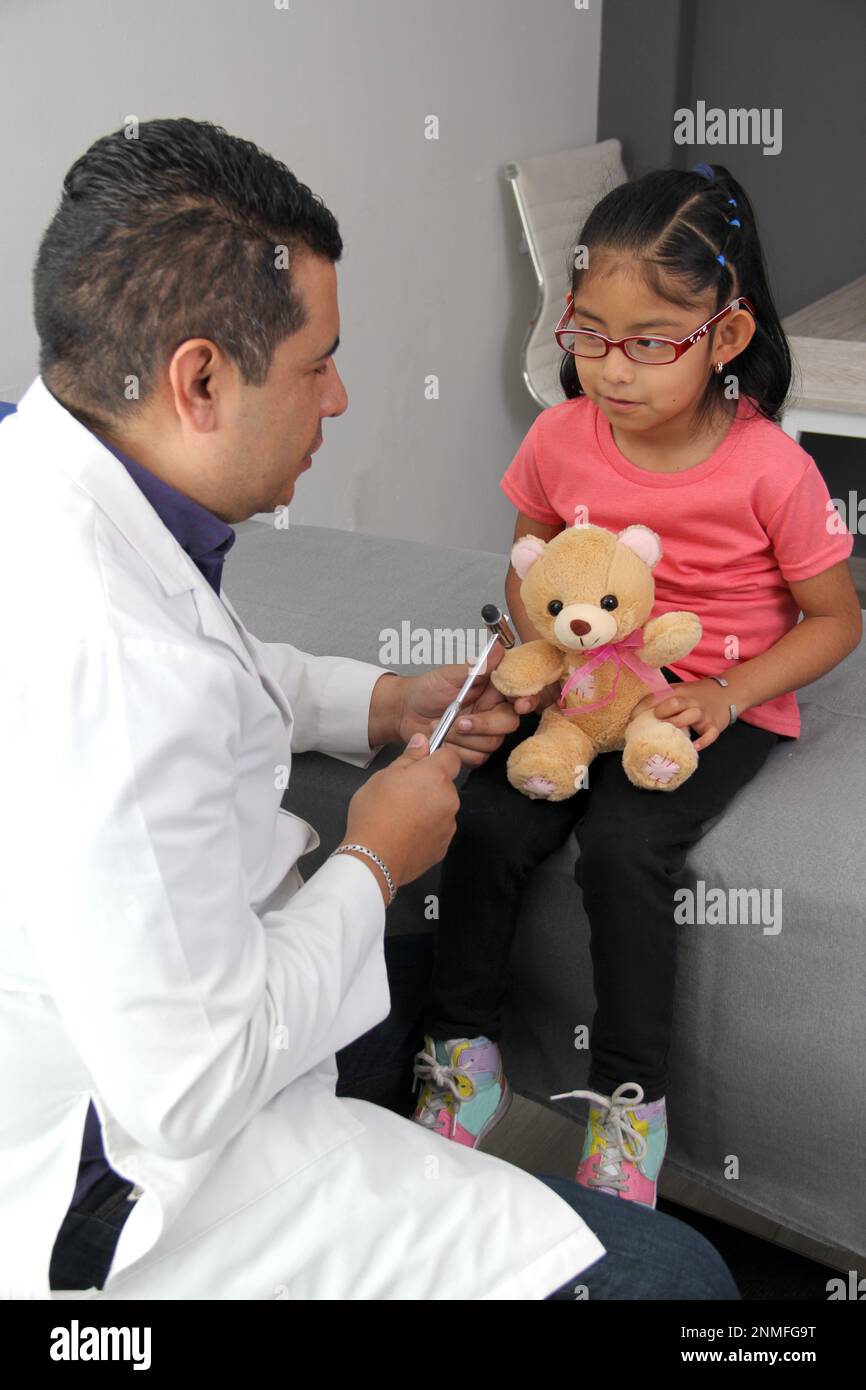 Latino pediatrician doctor checks his girl patient with autism spectrum ...