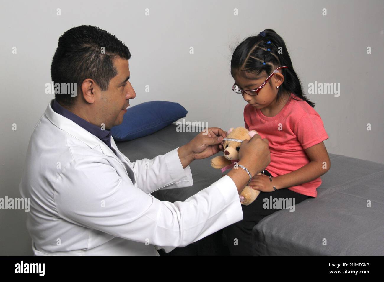Latino pediatrician doctor checks his girl patient with autism spectrum ...