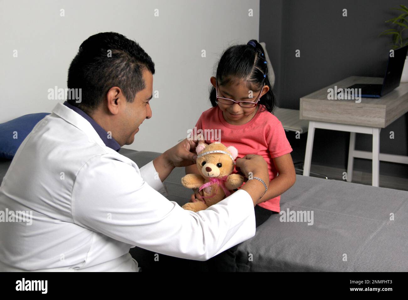 Latino pediatrician doctor checks his girl patient with autism spectrum ...