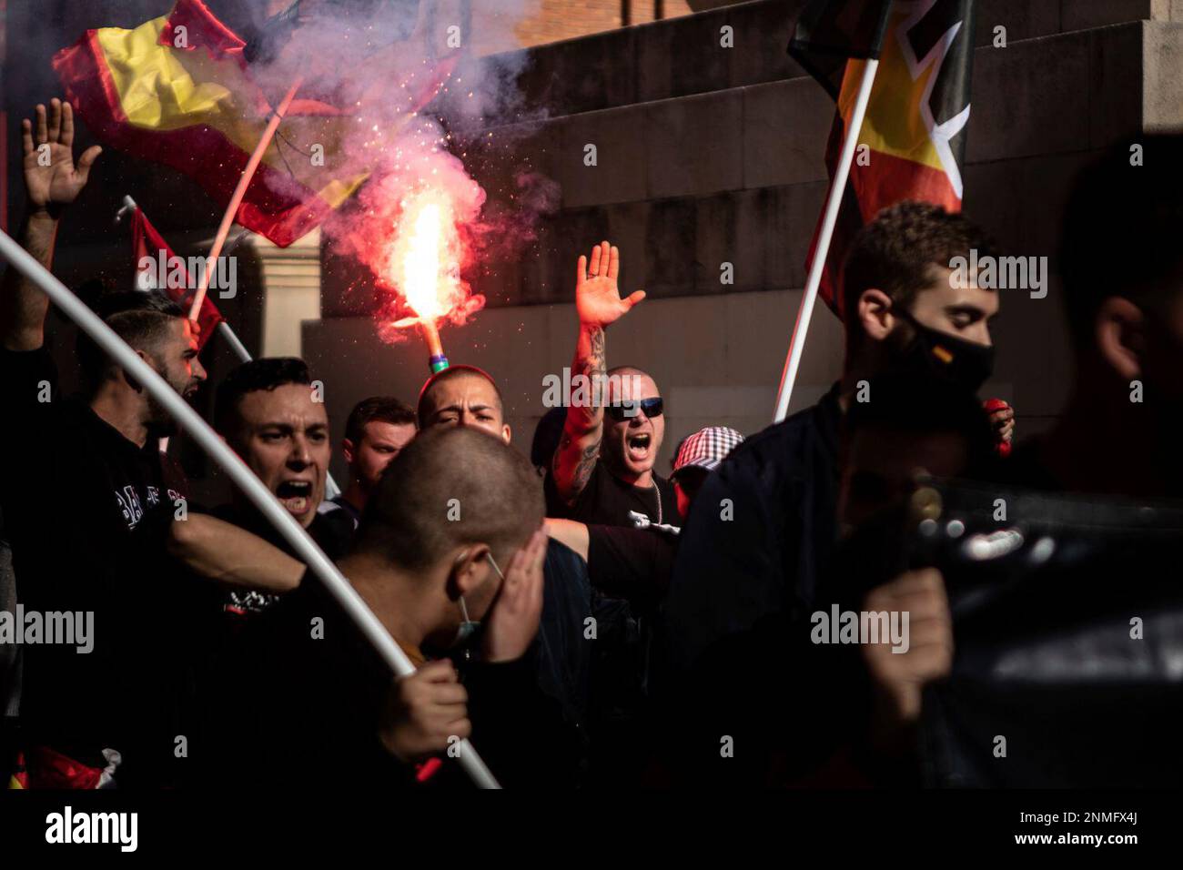Neo-Nazi youths with flares raise their arms during a neo-Nazi ...