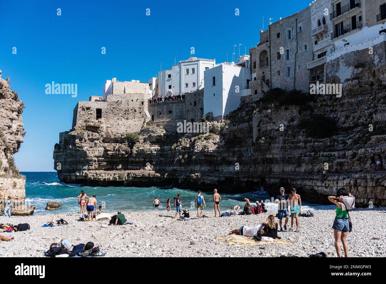 Bay and beach below the village on cliff, Mediterranean Sea, people as ...