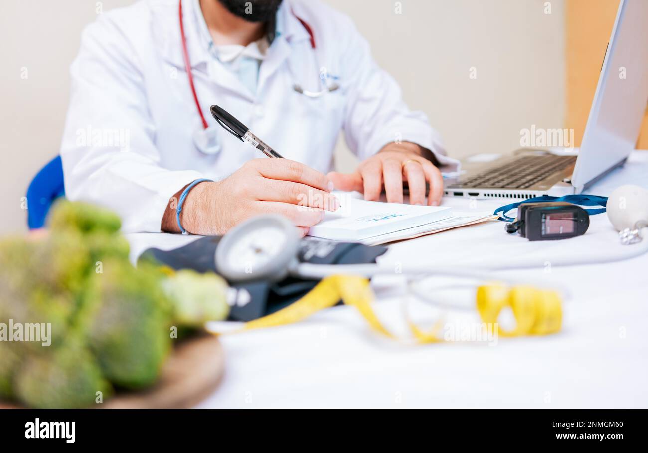 Close-up of nutritionist writing on notepad. Hands of male nutritionist ...