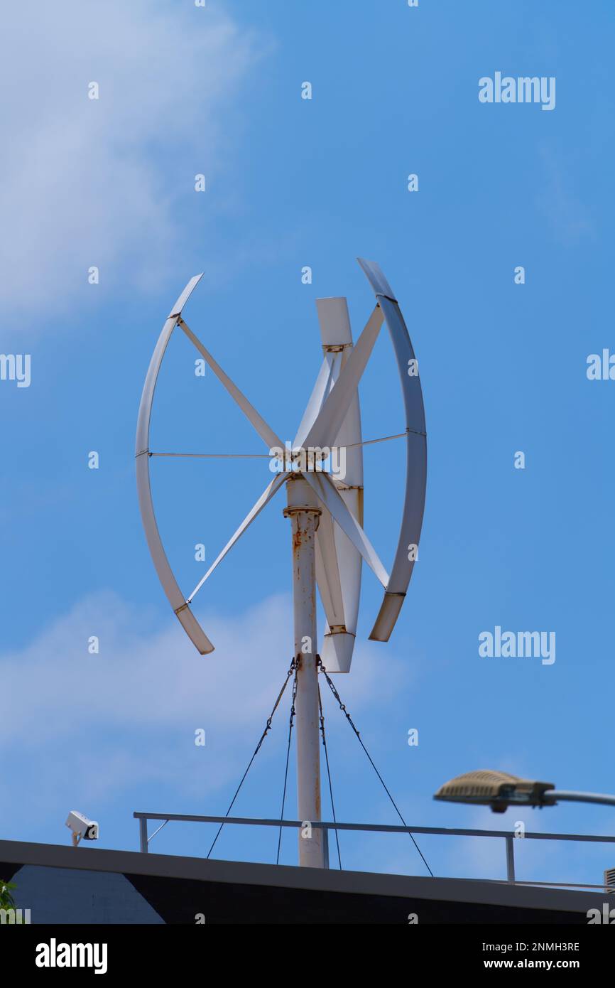 Wind turbine generator sits on top of a building with a blue sky ...