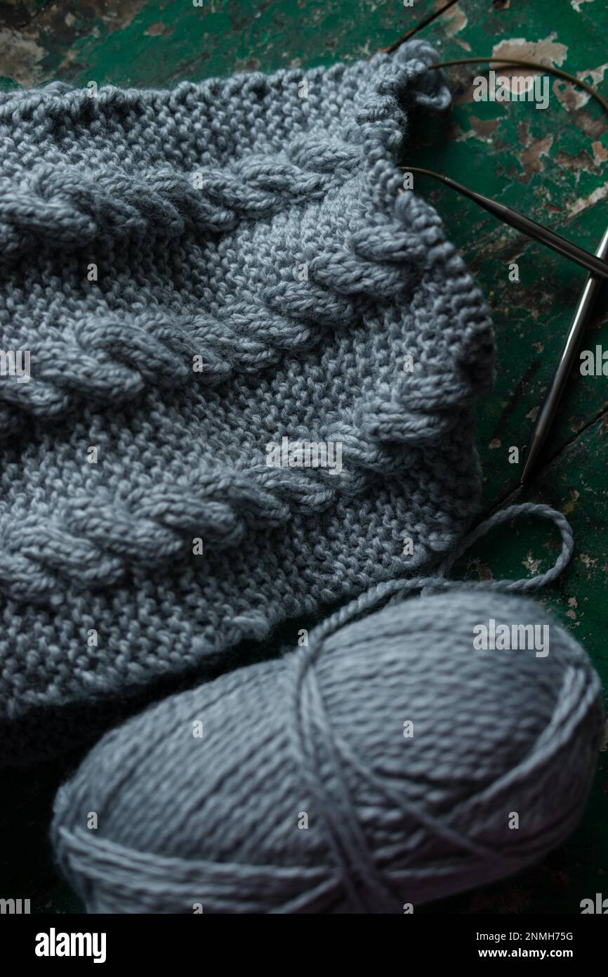 Grey knitted piece with knitting pattern and knitting needles Stock ...