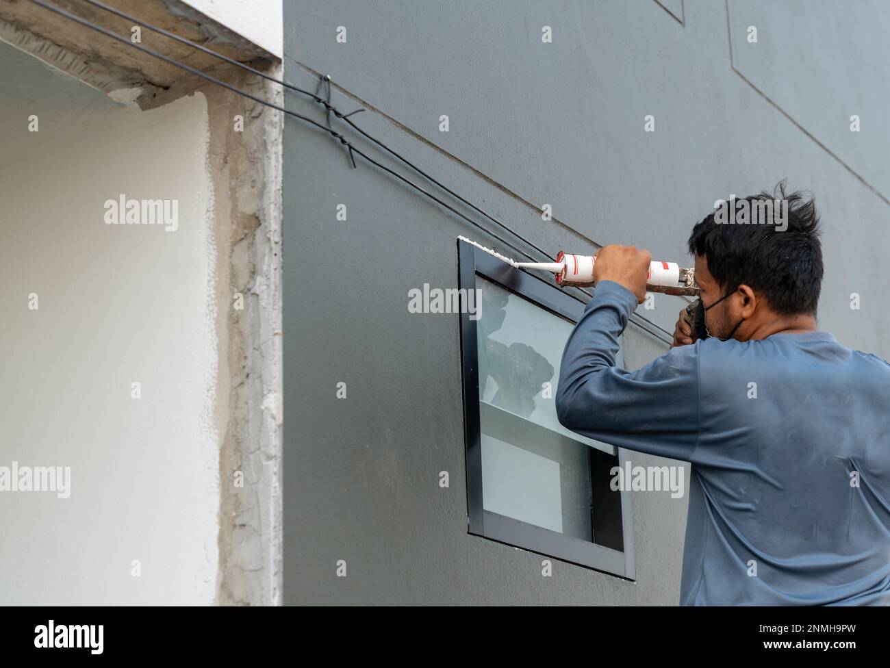 Closeup worker installing the windows with gun silicone in construction ...