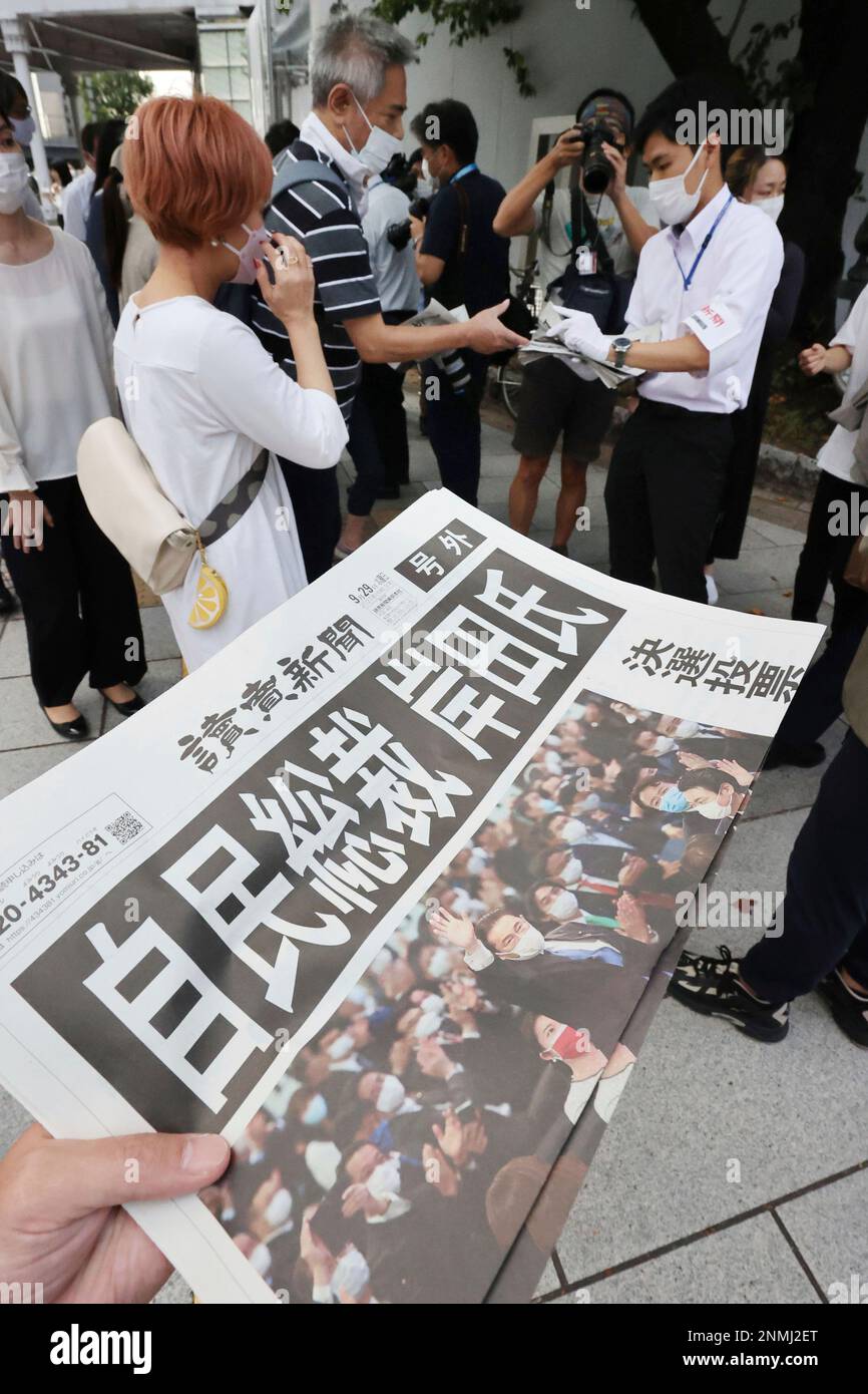 Pedestrian pick up an extra edition of the Yomiuri Shinbun newspaper ...