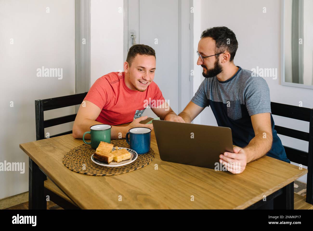 Two men sitting using laptop and phone Stock Photo - Alamy