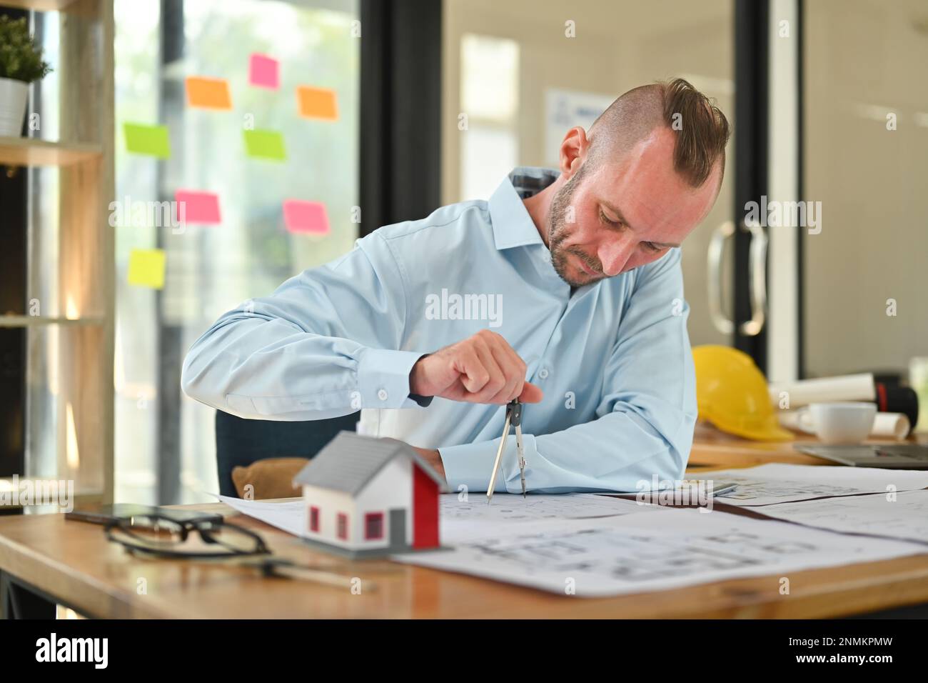 Focused architect man working on blueprint building plan, inspecting ...
