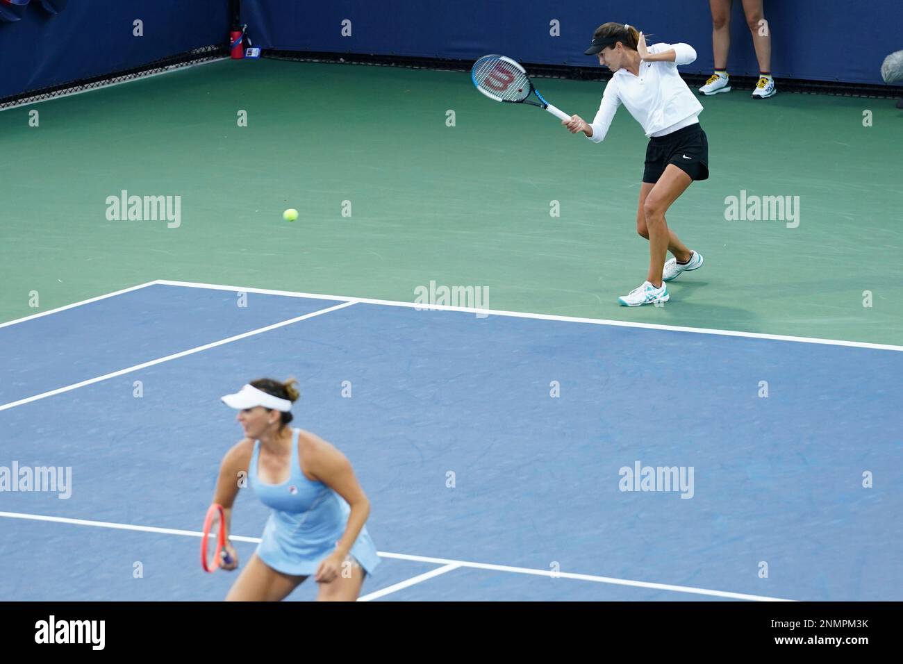 Anna Danilina returns a ball as Yaroslava Shvedova looks on during a ...
