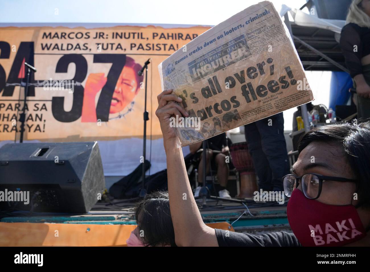 A protester holds an old newspaper during a rally to observe the 37th ...