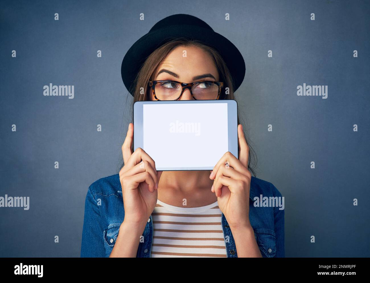 Read my lips. a quirky young woman posing with her tablet in front of ...