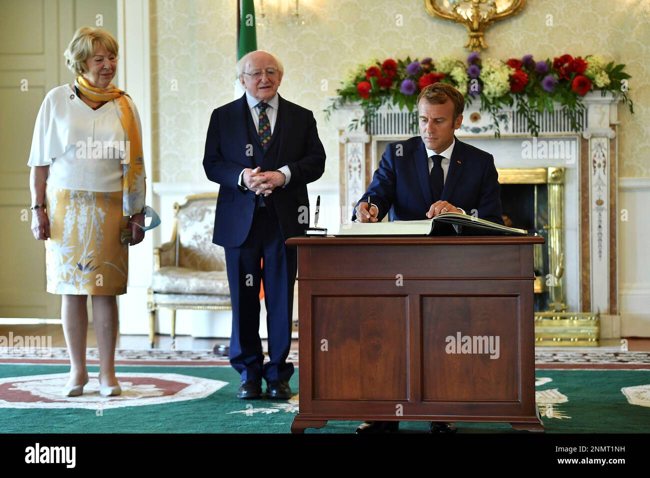 French President Emmanuel Macron signs a guest book as Irish President ...