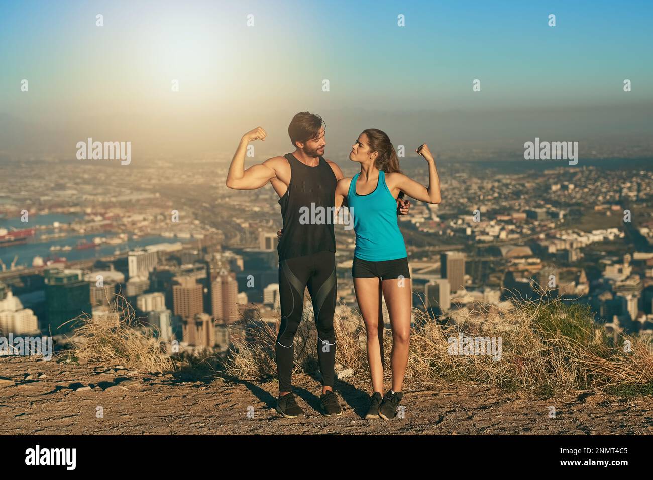 Find your strong. a young couple flexing their muscles while out for a ...